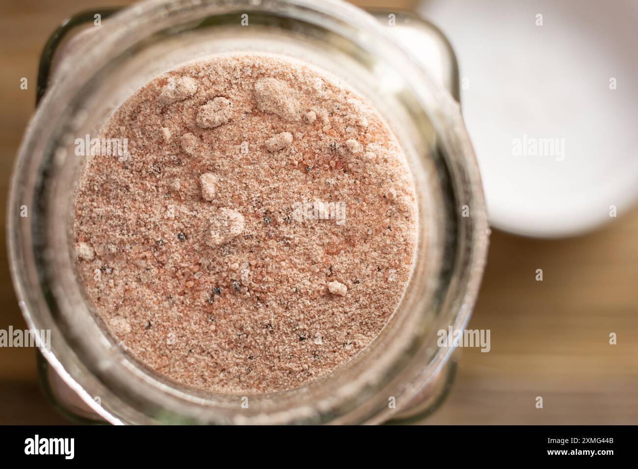 A top down closeup view of a condiment jar of kala namak rock salt ...