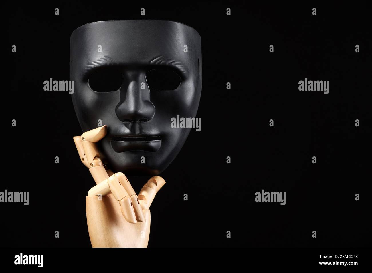 Wooden mannequin hand holding plastic mask on black background, space ...