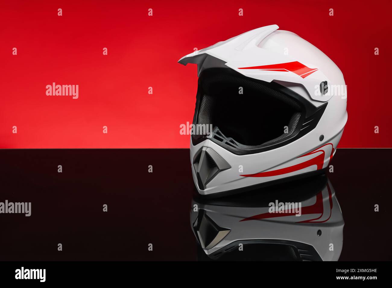 Modern motorcycle helmet with visor on mirror surface against red ...