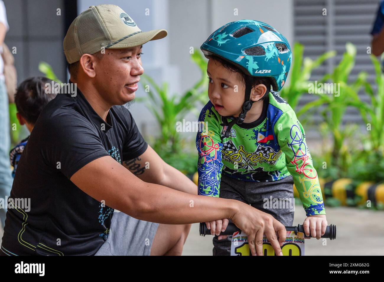 Iloilo City, Philippines. 28th July, 2024. A father talks to his son before a push bike race for ...