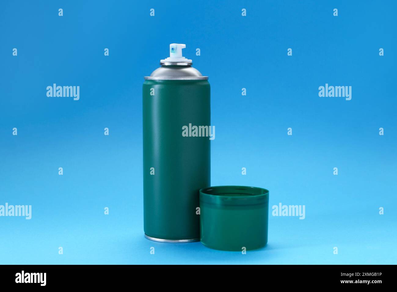 Green spray paint can on light blue background Stock Photo - Alamy