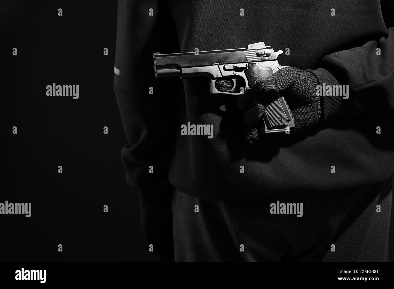 Man hiding gun behind his back on black background, closeup. Armed ...