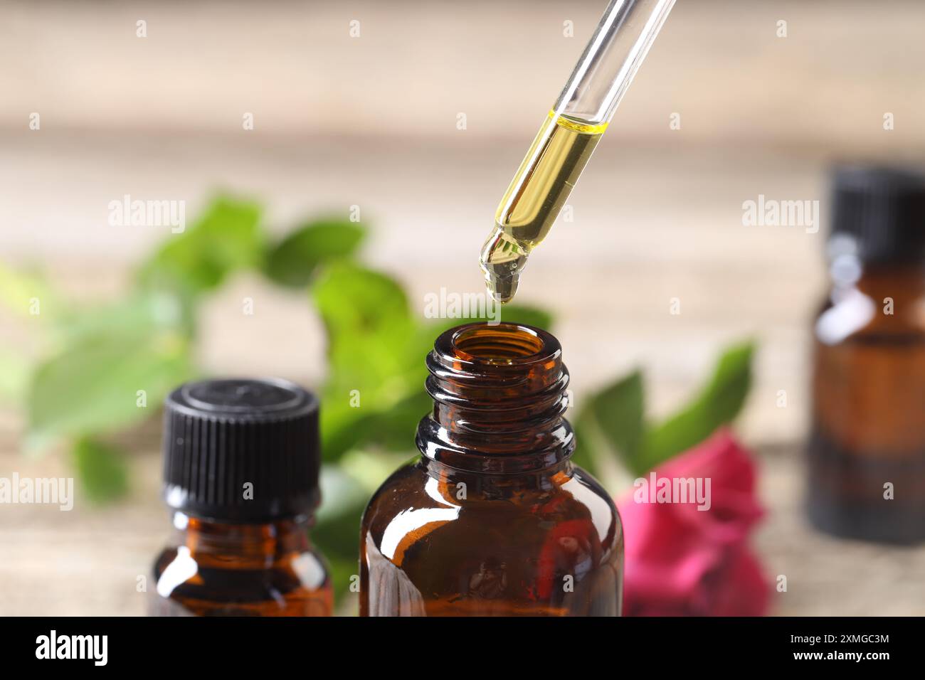 Essential oil dripping from pipette into bottle at table, closeup Stock ...