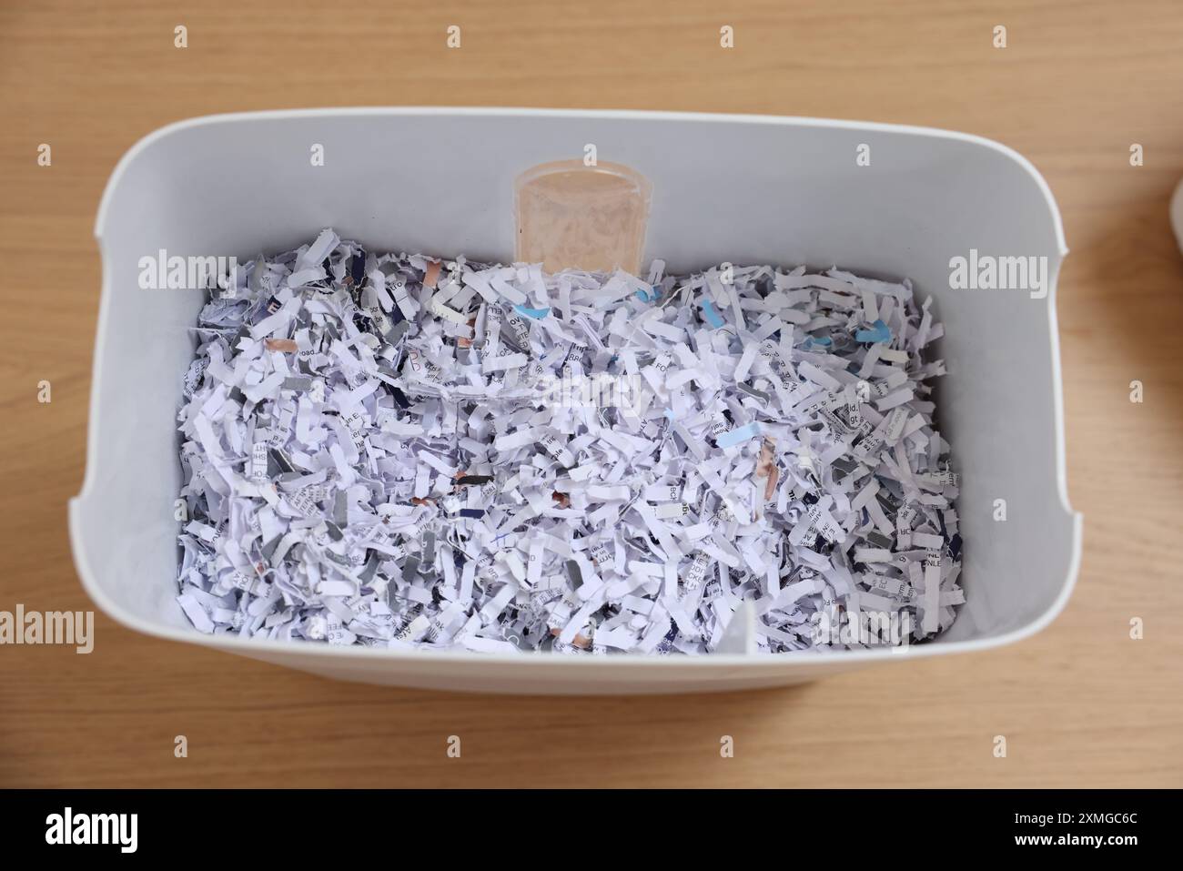 Shredded paper strips in bin on wooden table, top view Stock Photo - Alamy