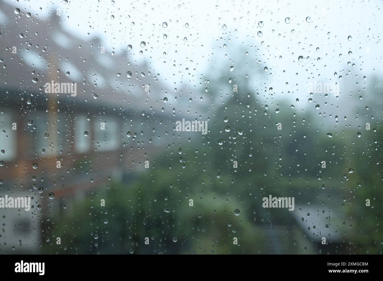 View on buildings through window with water droplets on rainy day ...