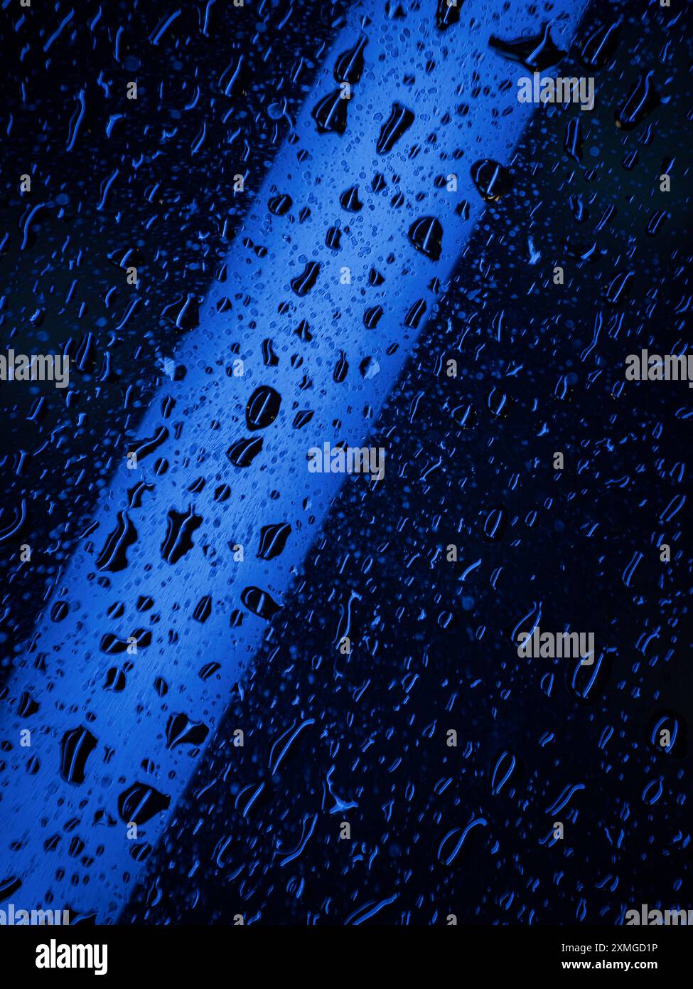 Close-up view of raindrops on glass with bright blue light reflection ...