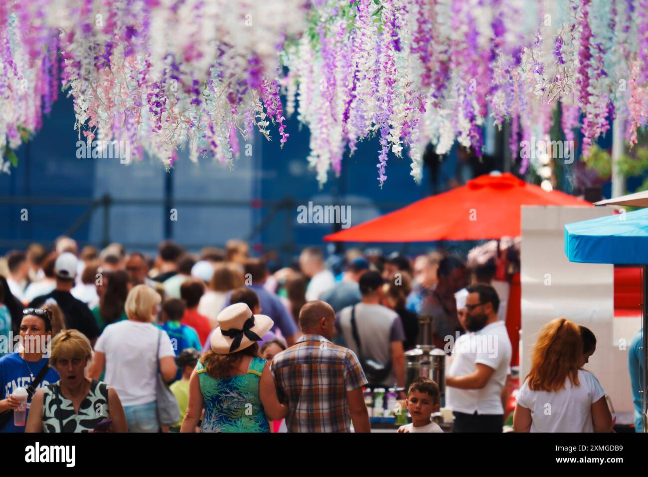 A large crowd of people enjoying an outdoor festival, with colorful ...