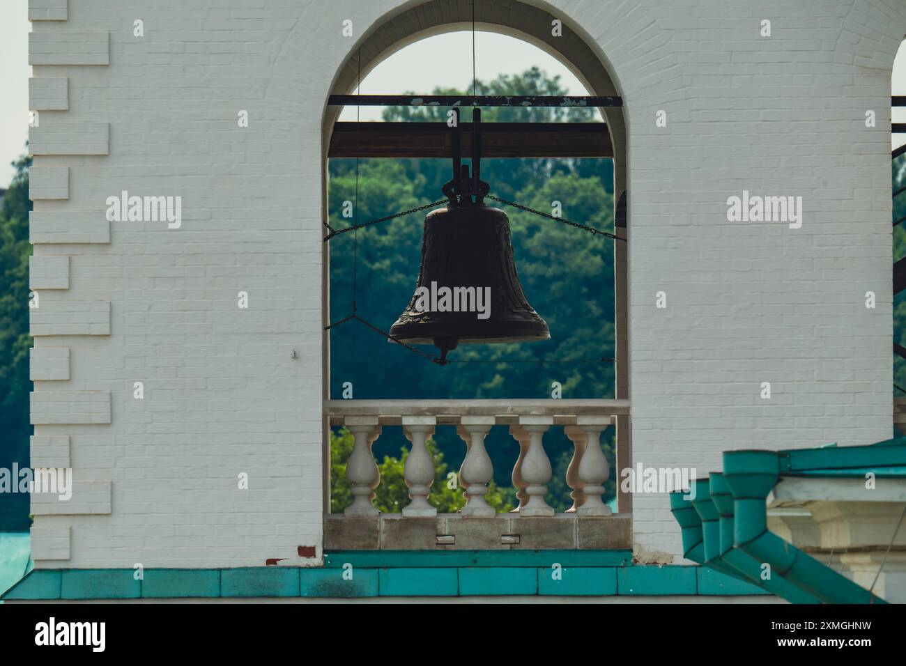 A historic bell hanging within an arched window of a white building ...