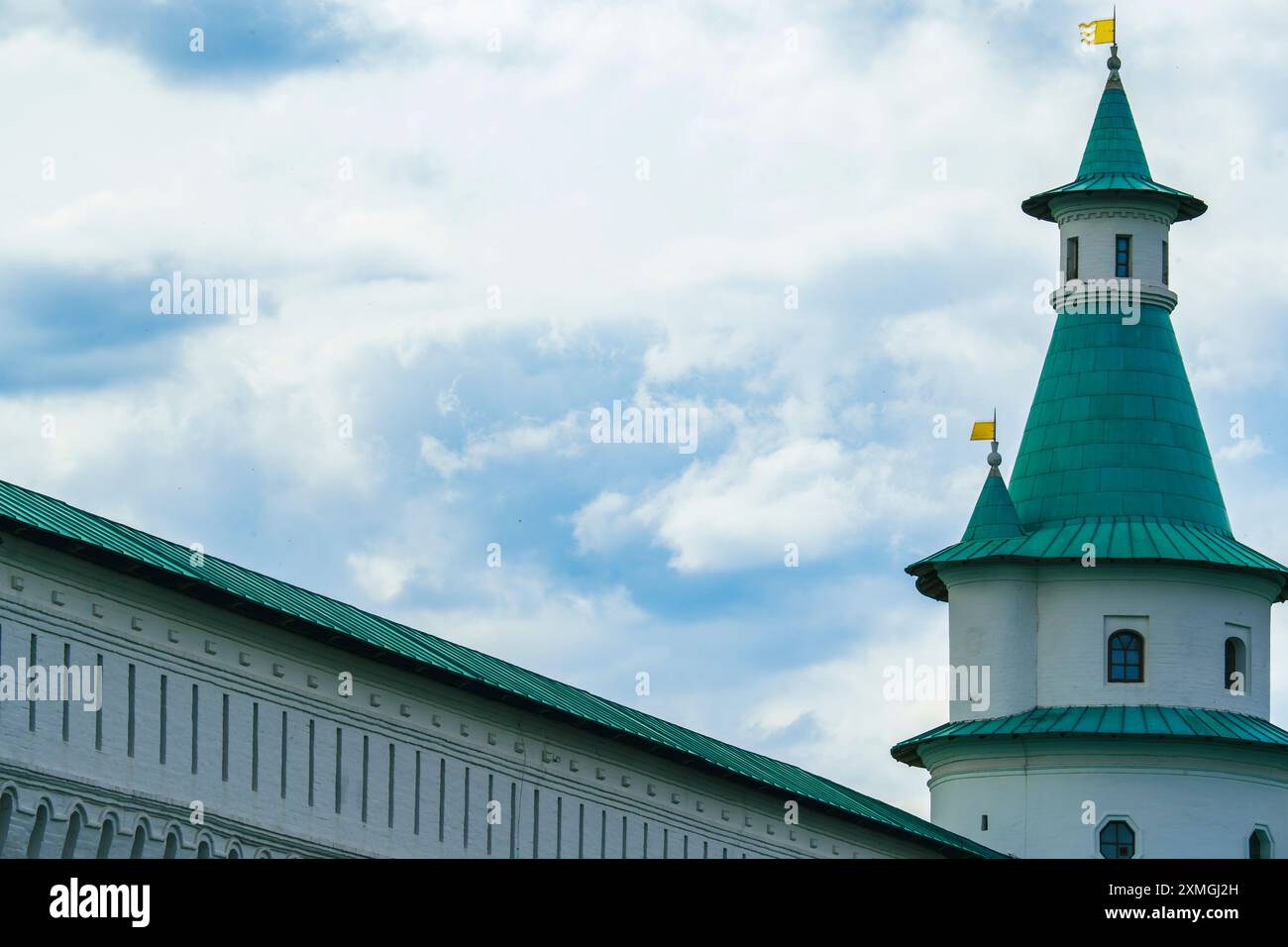 Historic monastery towers with green roofs and yellow flags under a ...