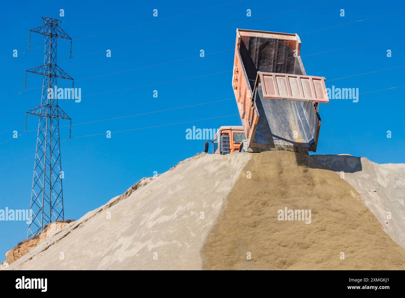 Dump truck unloading sand onto a pile near the power lines Stock Photo ...