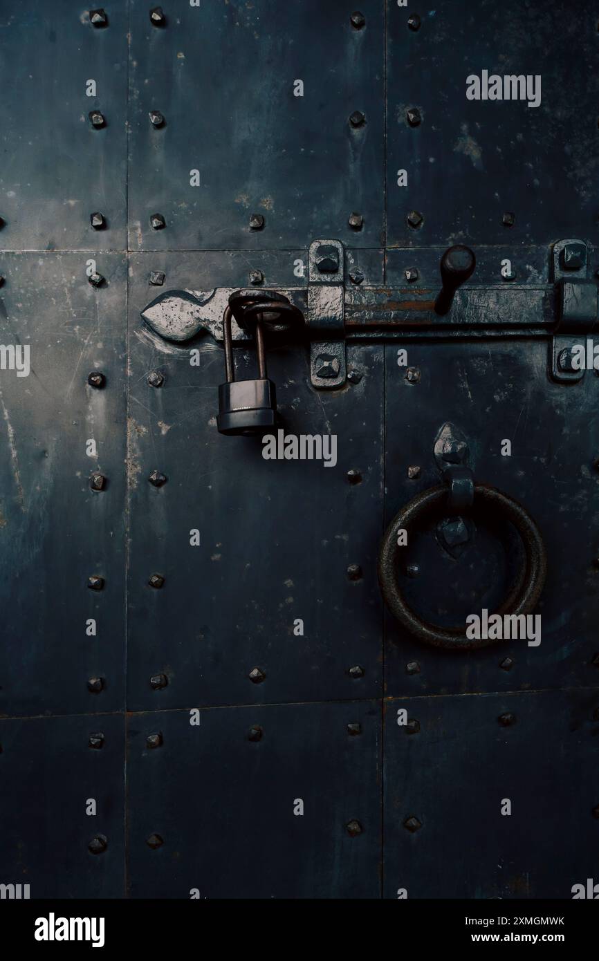 A close-up shot of a rustic metal door featuring a heavy-duty lock and ...