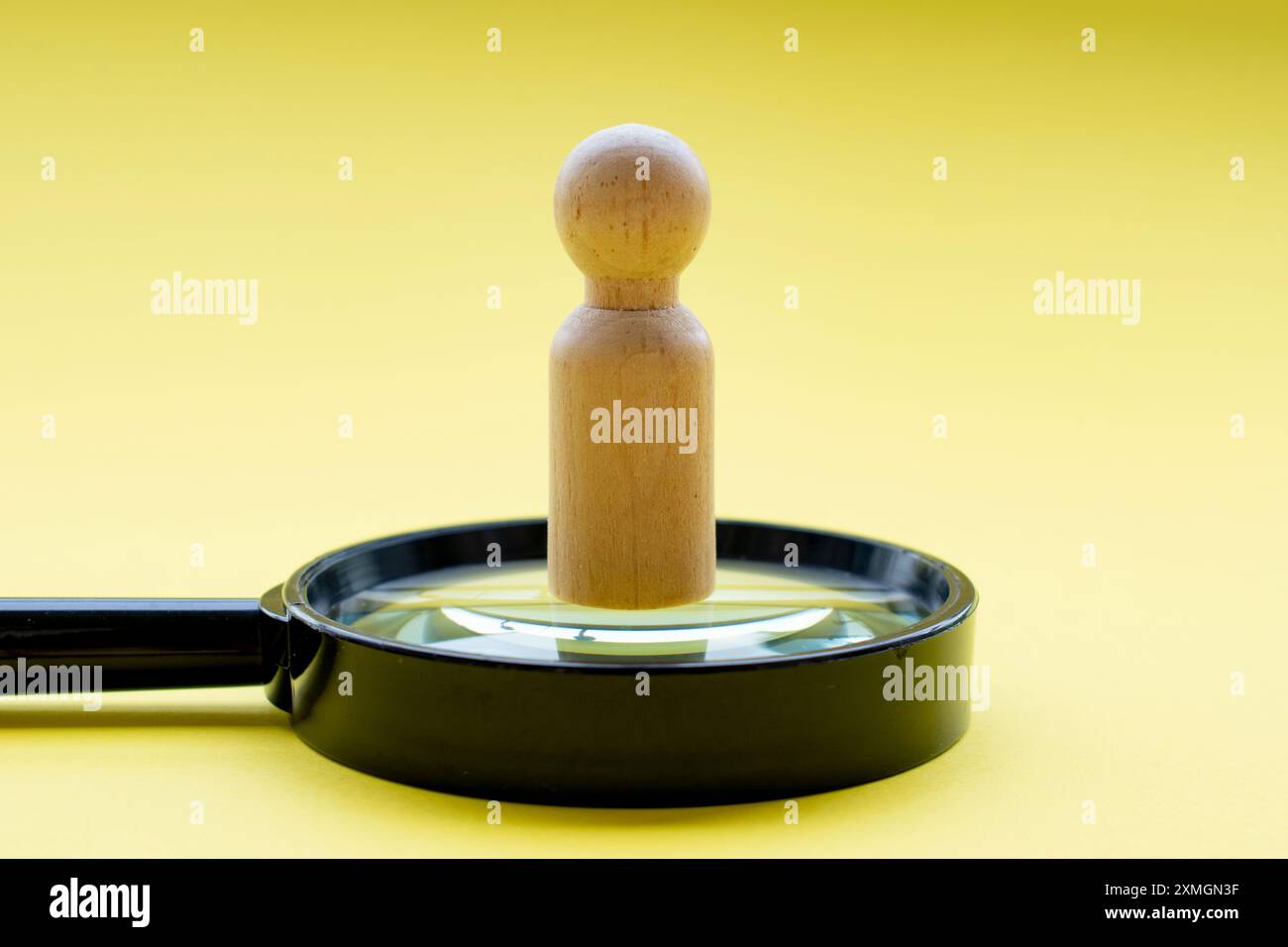 Wooden figure on top of magnifying glass representing the chosen one or ...