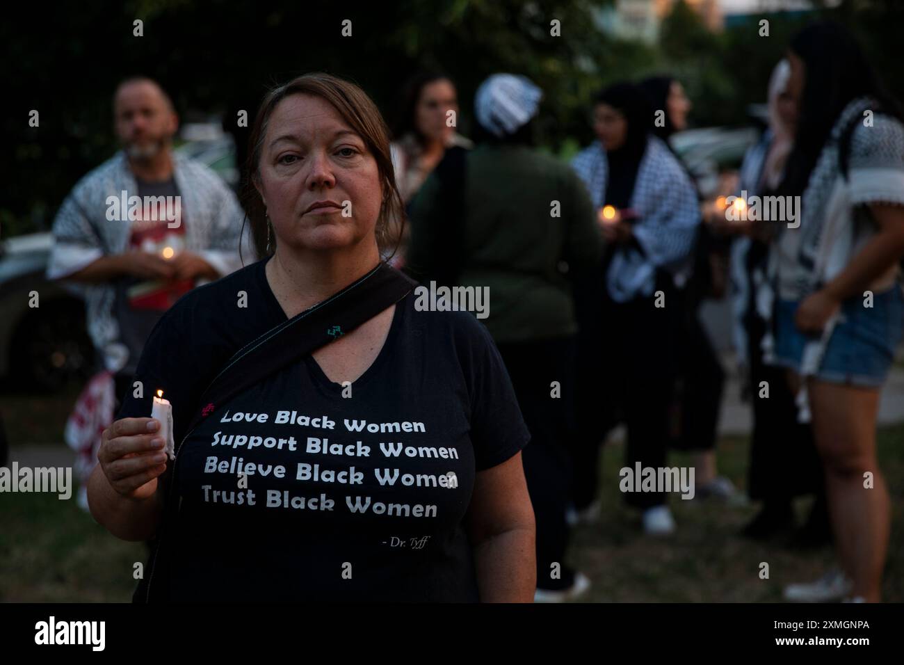 A mourner is holding a candle while attending a vigil for Sonya Massey ...