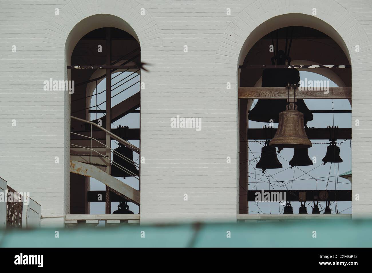 A close-up view of large bells hanging inside the arches of a white ...