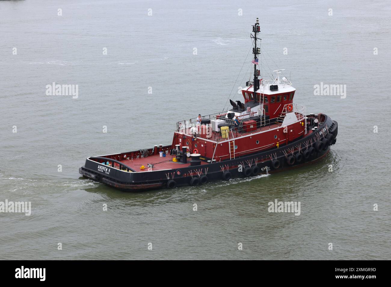 A modern small tugboat cruises in the water area of the port. Preparing ...