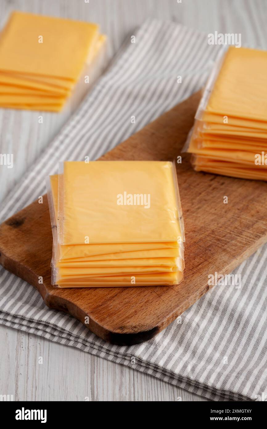 Yellow Cheddar American Cheese Stacked Slices on a wooden board, side ...