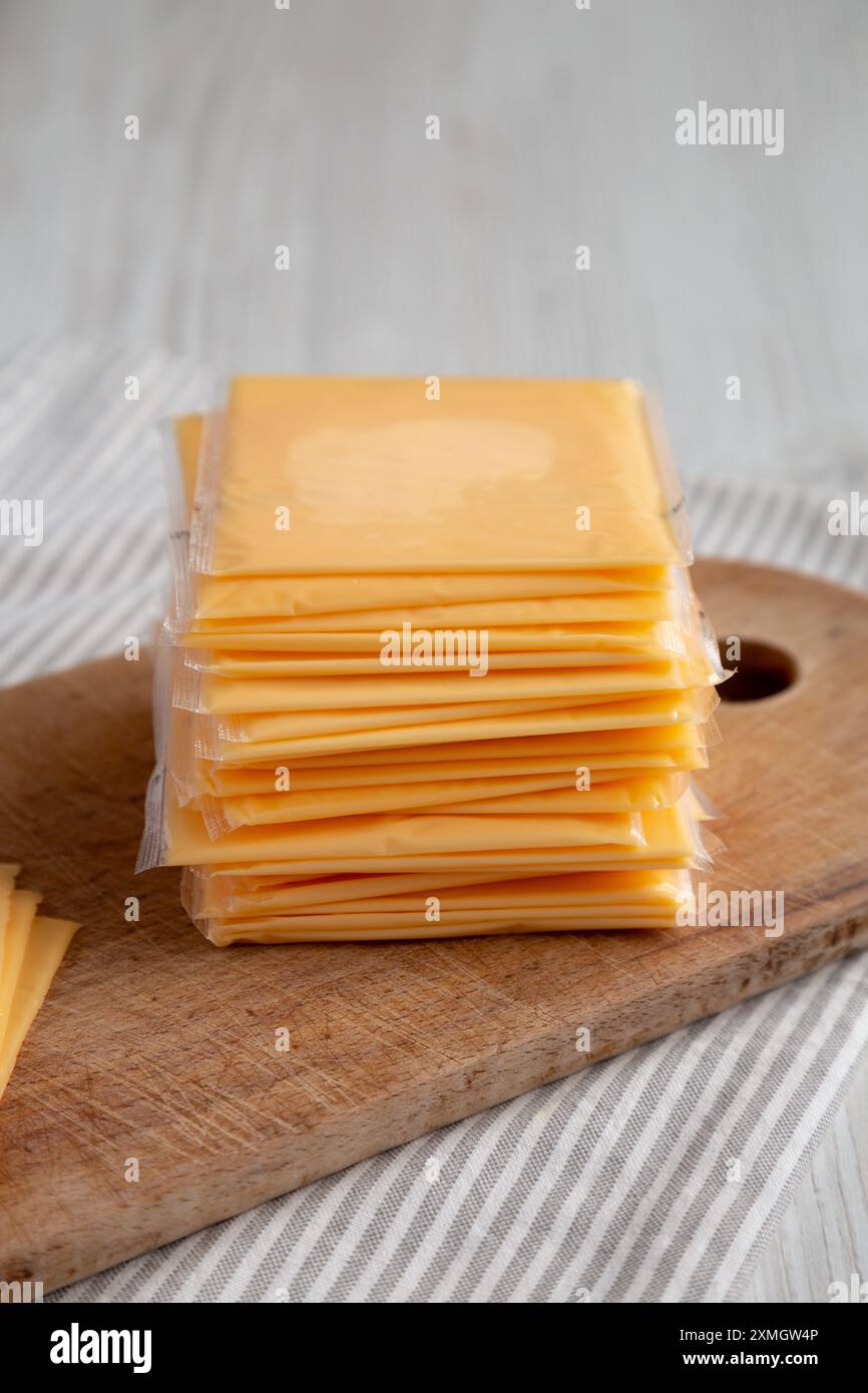Yellow Cheddar American Cheese Stacked Slices on a wooden board, side ...