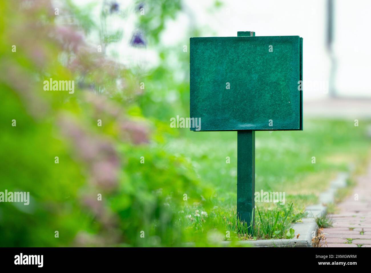 Close-up of a green information board in a lush garden with flora. Well ...