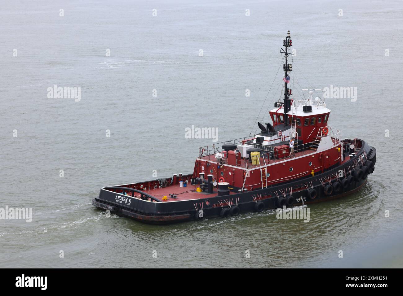 A modern small tugboat cruises in the water area of the port. Preparing ...