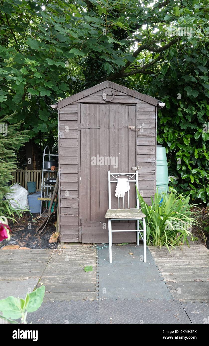 A small garden shed on an allotment with a chair ready for a rest from ...