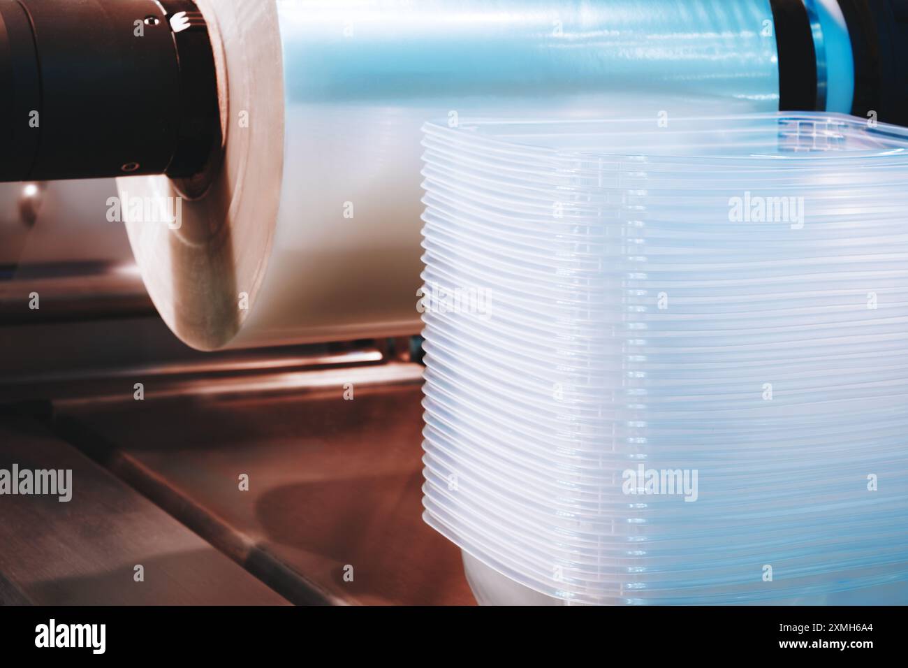 A roll of plastic film is used to wrap a stack of plastic plates ...