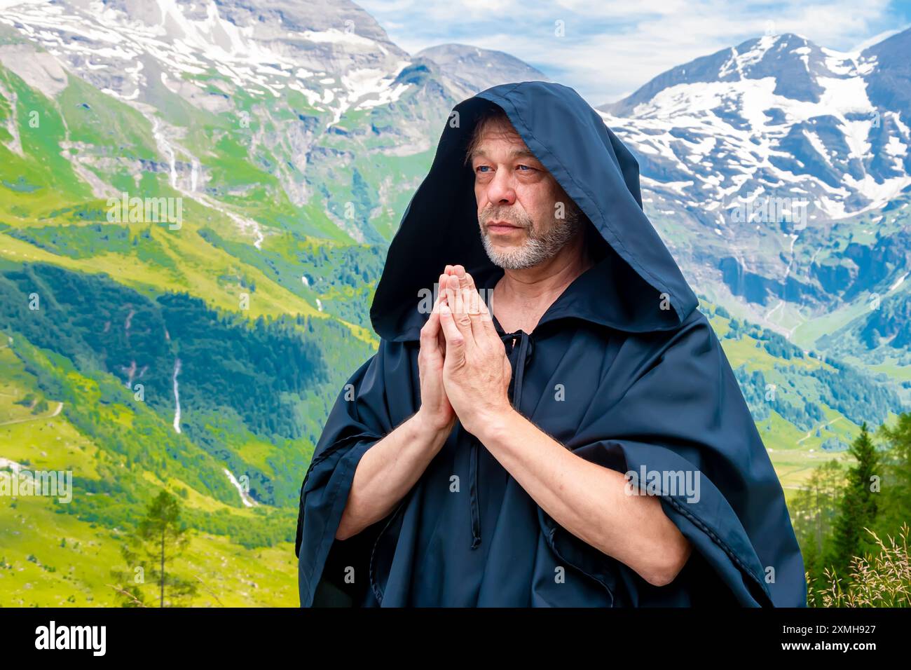 Mysterious elderly male monk wearing a hooded cloak, standing amidst ...