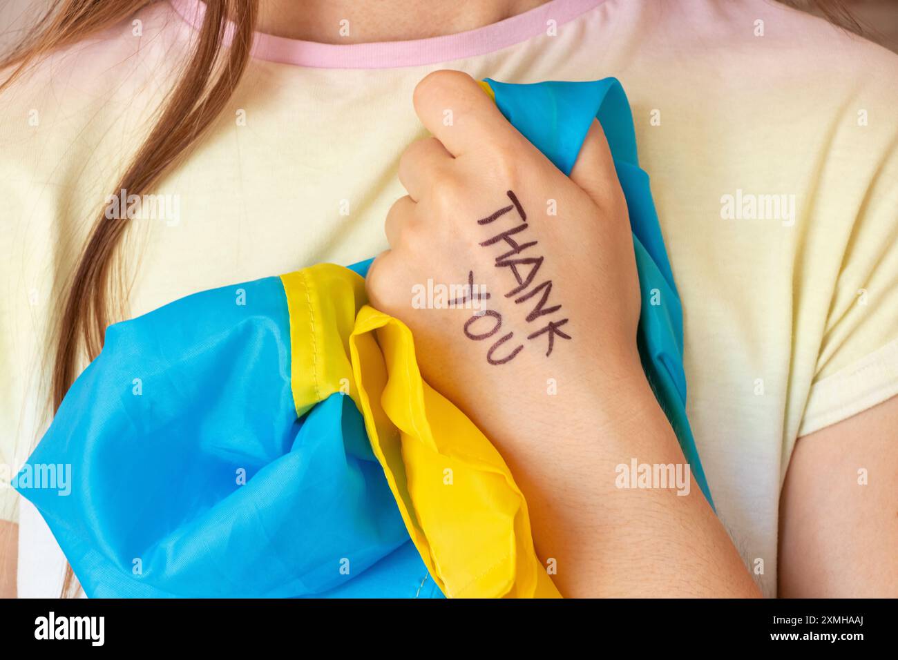 The girl holds a Ukrainian flag in her hand and on her hand is written ...