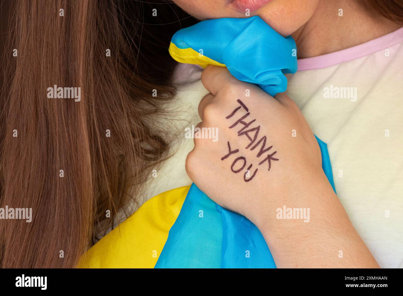 The girl holds a Ukrainian flag in her hand and on her hand is written ...