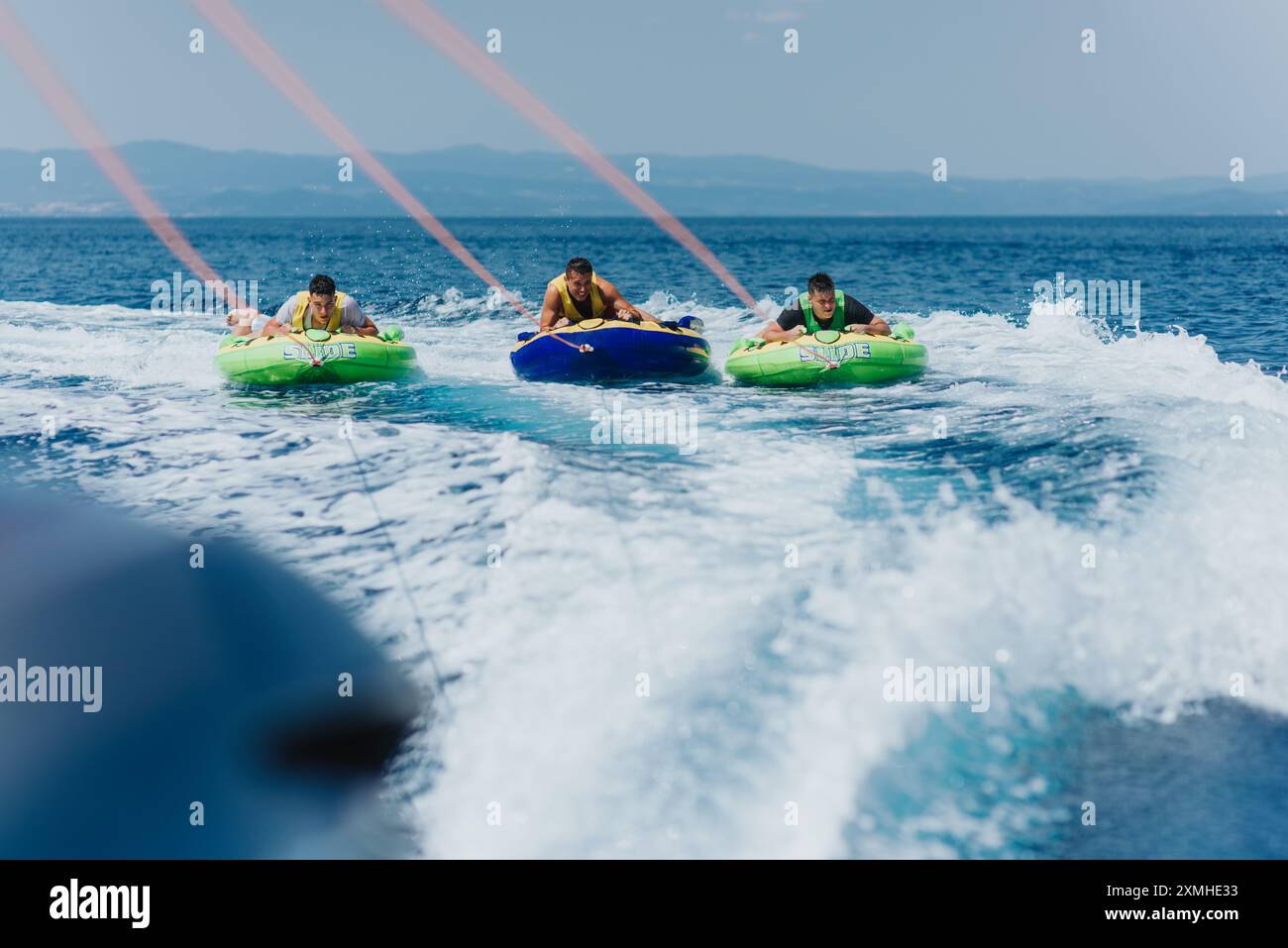 Friends enjoying speedboat tubing on the sea during summer vacation ...