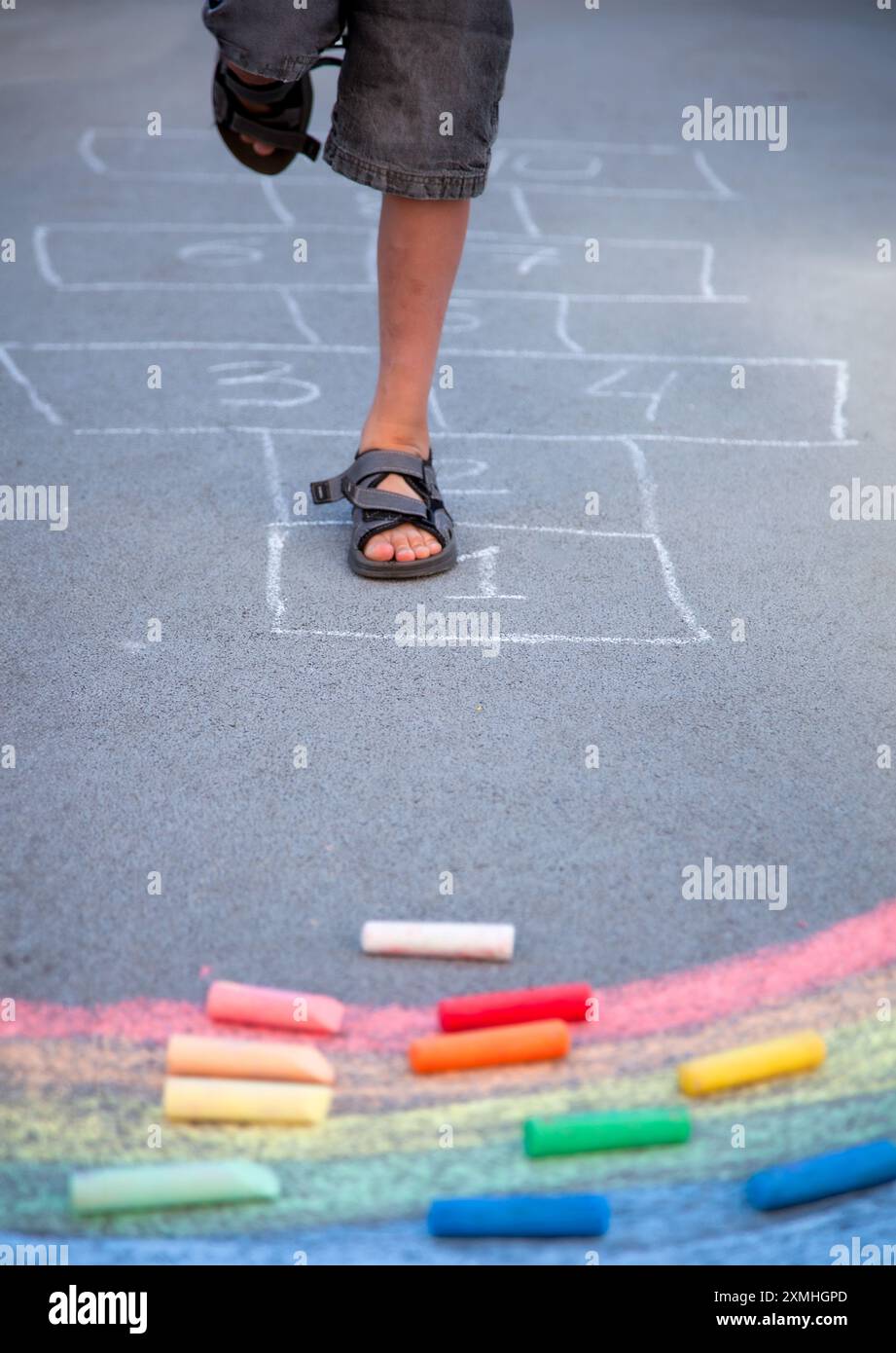 Hopscotch drawn with chalk on the pavement. Children's feet. Jumping on ...