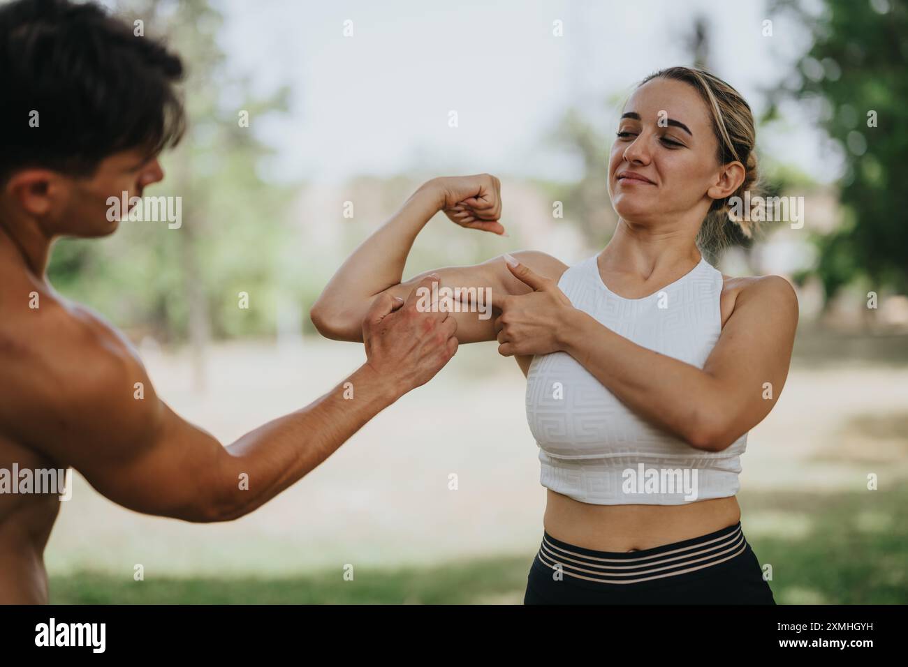 Happy woman flexing her biceps outdoors with a supportive friend Stock ...