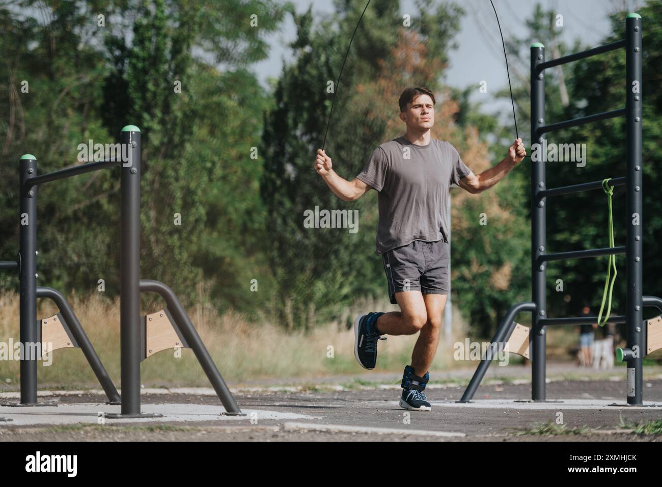 Man doing a jump rope workout outdoors in a park, performing ...