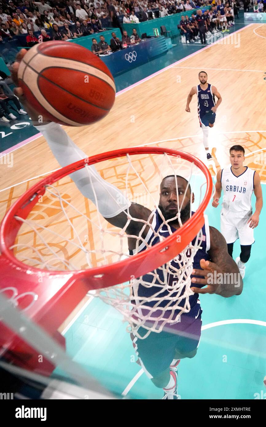 LeBron James, left, of the United States, dunks as Bogdan Bogdanovic ...