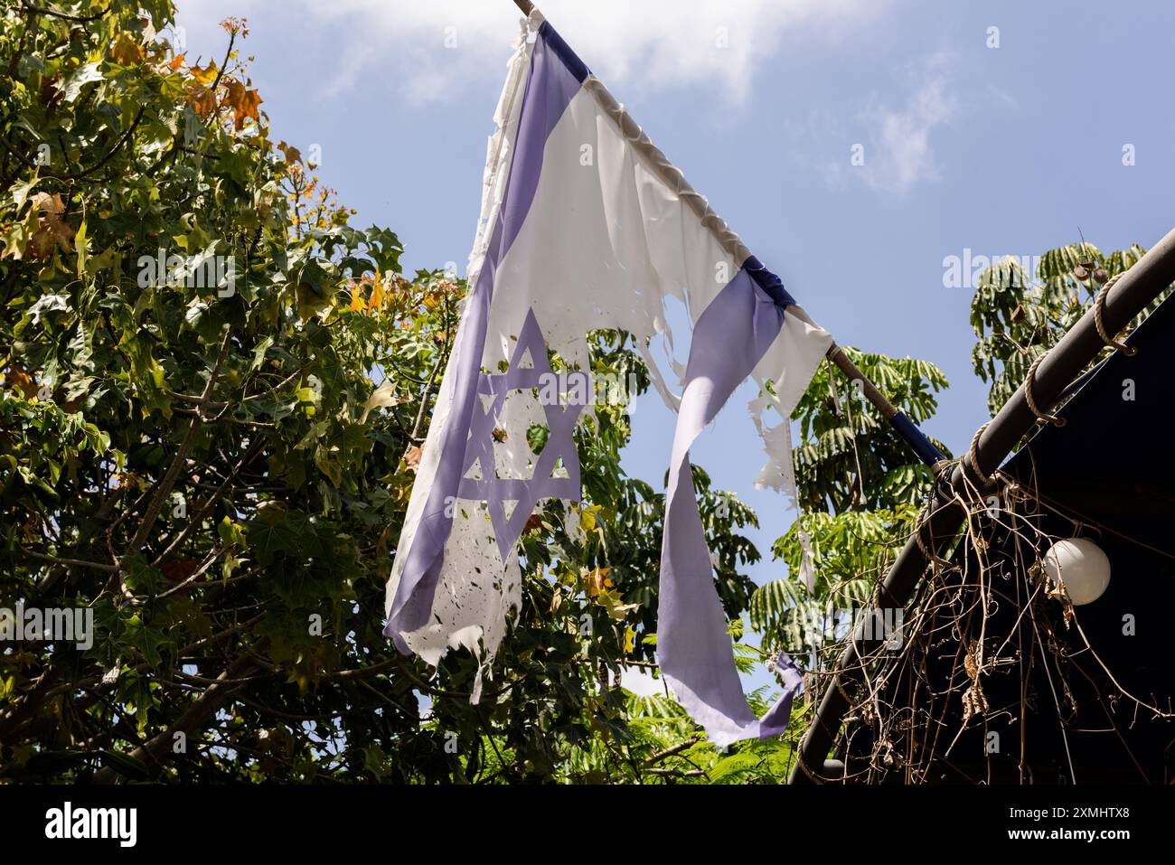 A torn and tattered Israeli flag hangs from a rooftop on Moshav Netiv ...