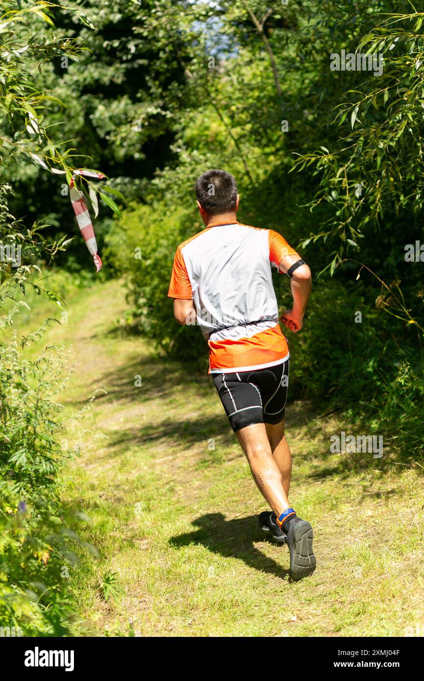Rear view on active young man running during the triathlon competition ...