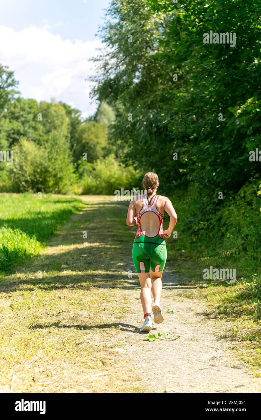 Rear view on active young man running during the triathlon competition ...