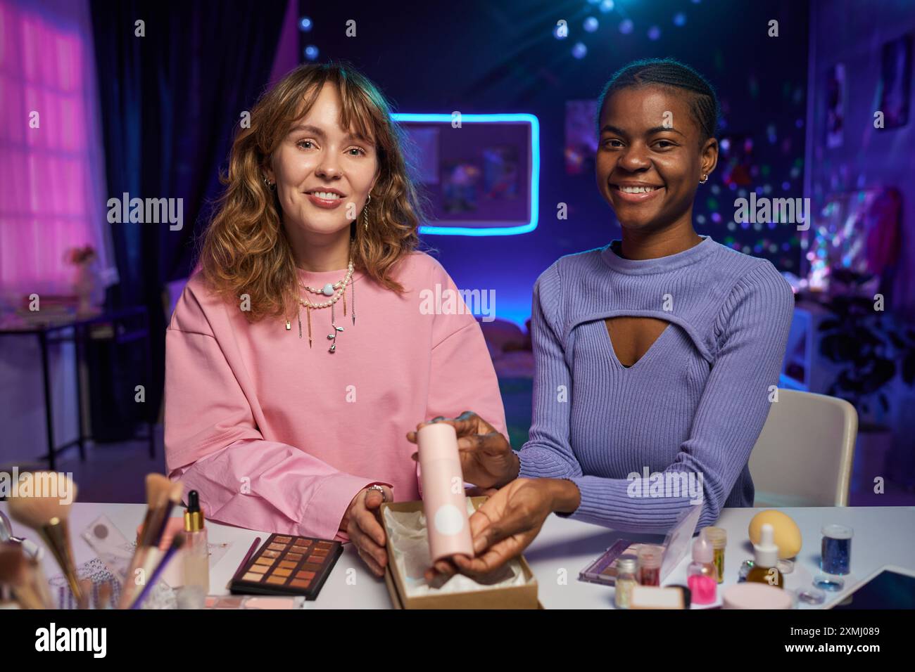 Portrait of two smiling girls reviewing skincare and make up products ...