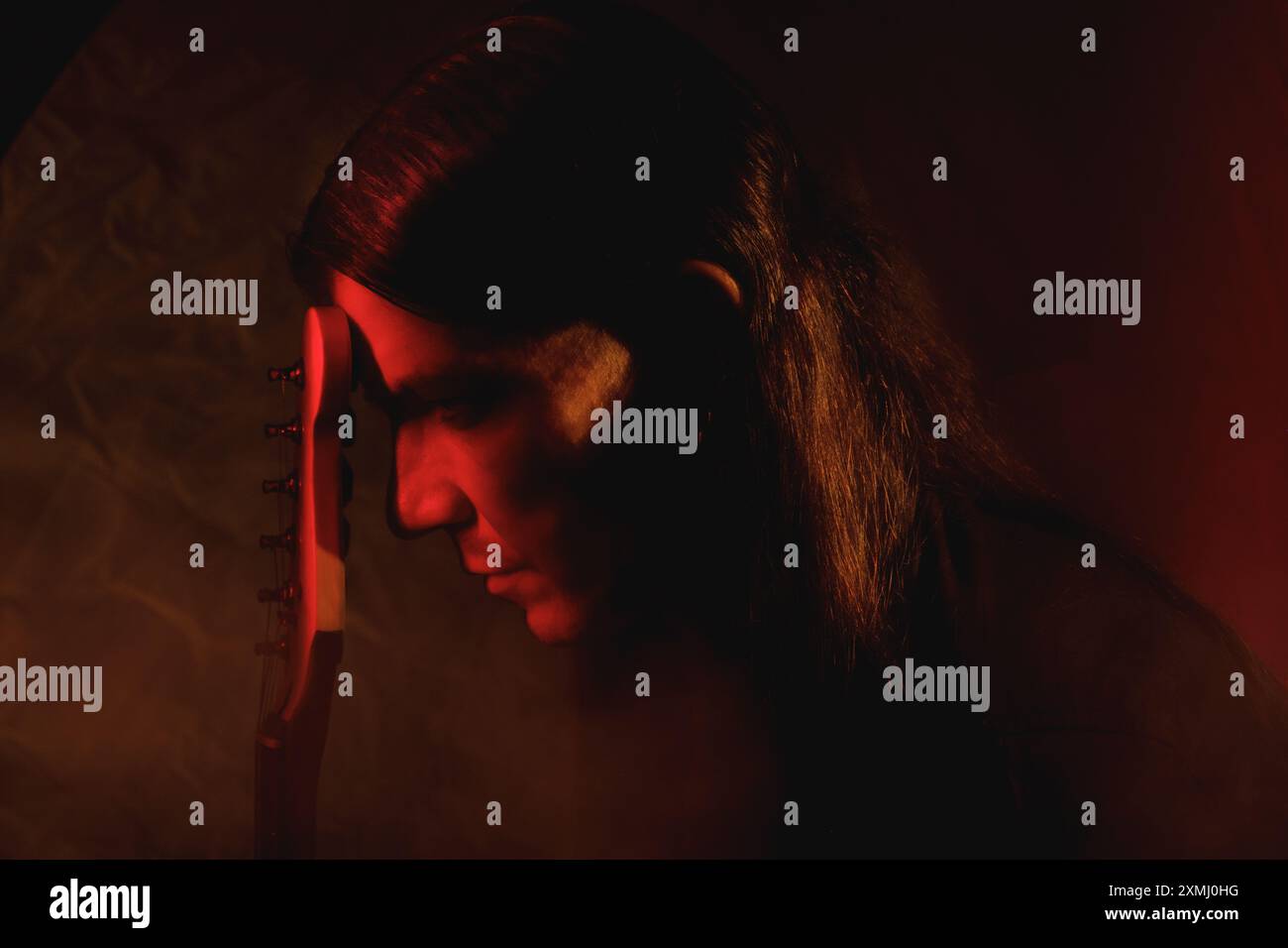 A portrait of an electric guitarist in a dramatic pose, resting his ...