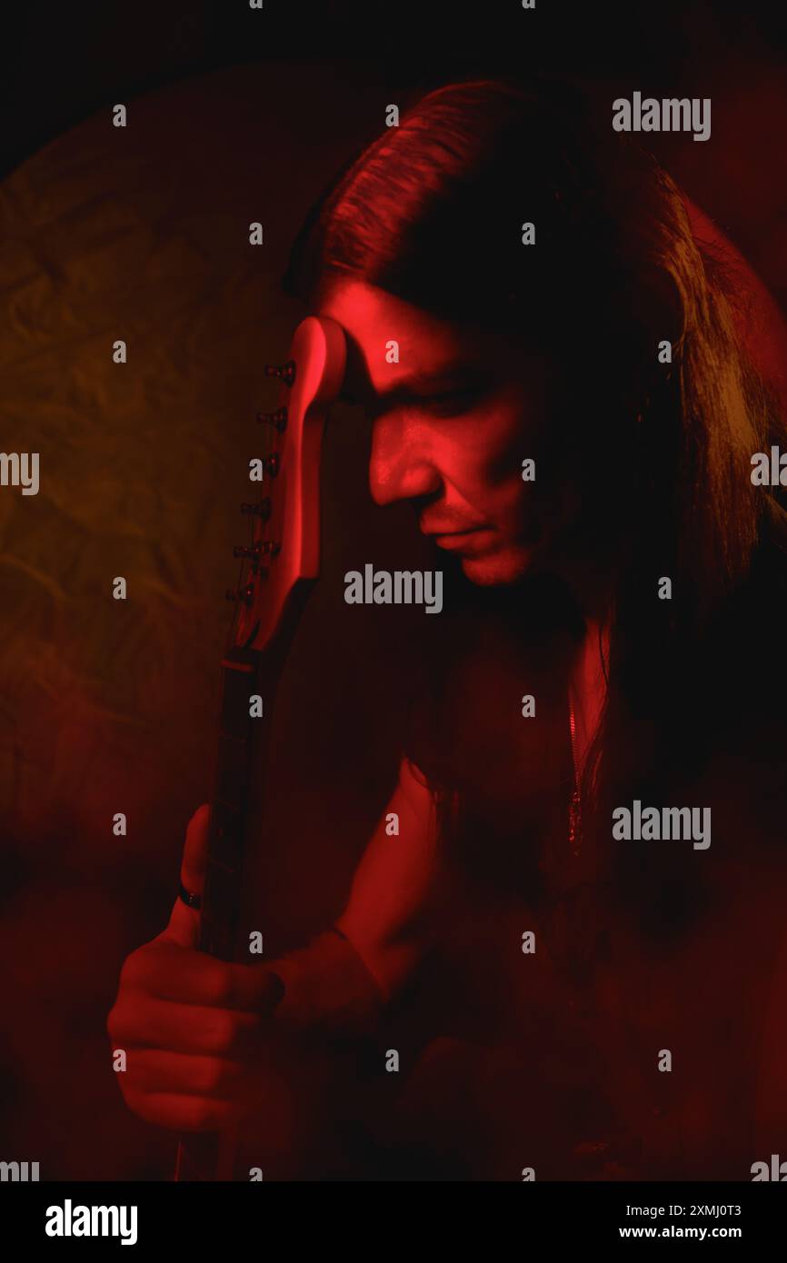 A portrait of an electric guitarist in a dramatic pose, resting his ...