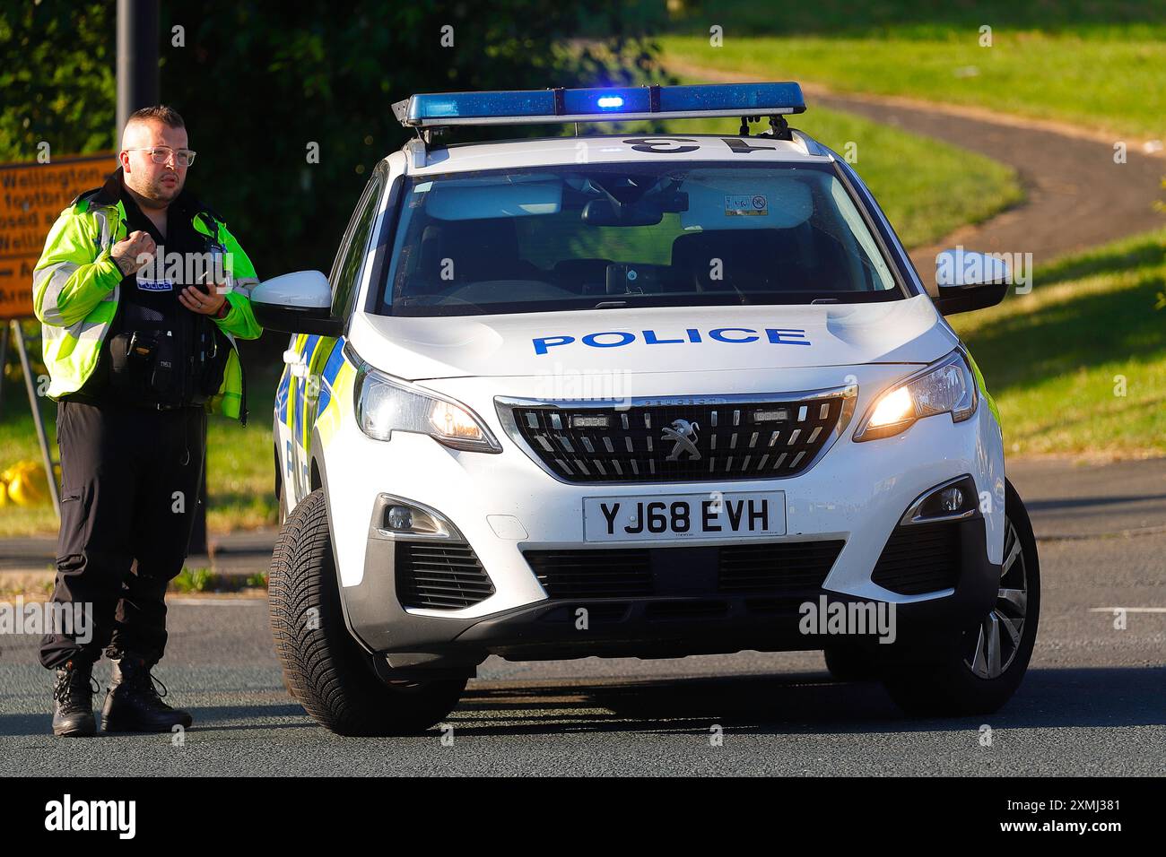 A Police officer stood by his vehicle that is used as a roadblock at an ...