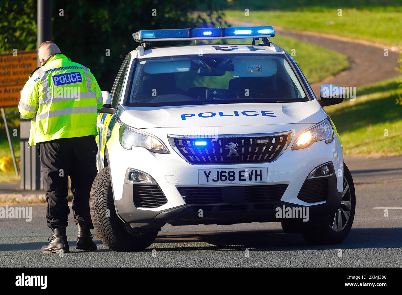 A Police officer stood by his vehicle that is used as a roadblock at an ...
