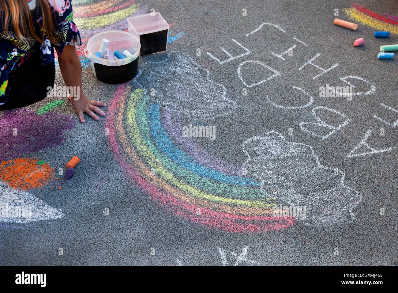 Children draw a rainbow on the asphalt with colored chalk. Sidewalk ...