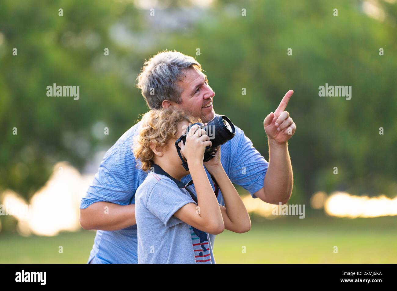 Child learning to take photos. Kid photographer. Little boy watching ...