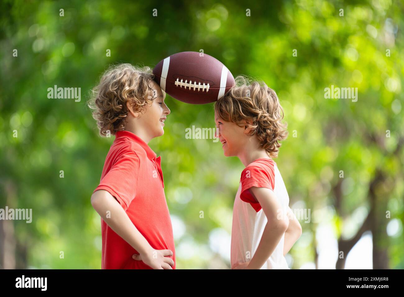 Family playing American football. Kids play rugby in sunny summer park ...