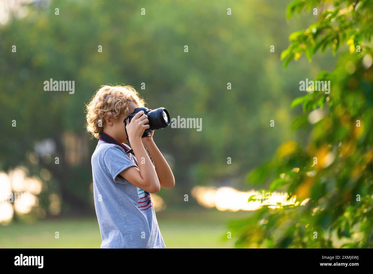 Child learning to take photos. Kid photographer. Little boy watching ...