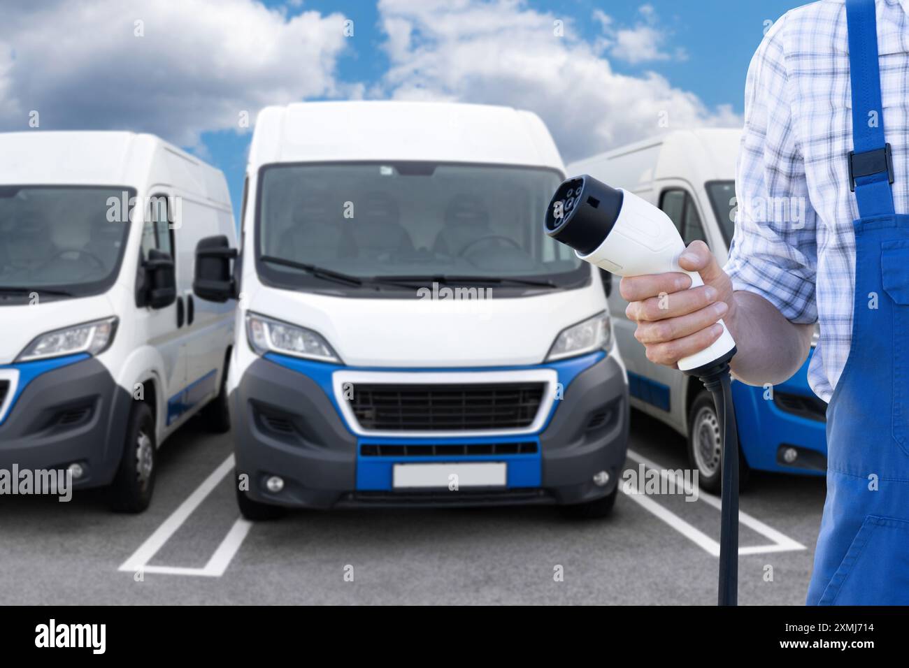 Man holds electric vehicle charging plug. Electric vans in the ...
