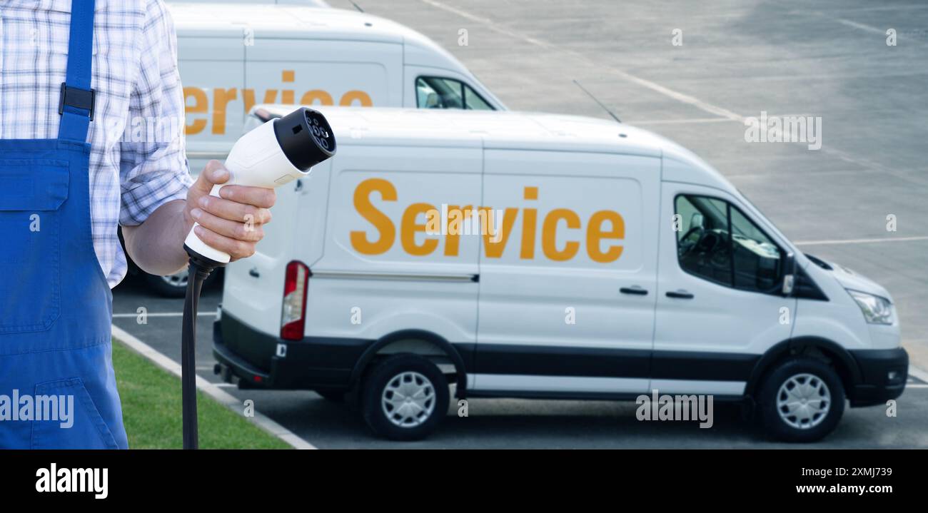 Man holds electric vehicle charging plug. Electric vans in the ...