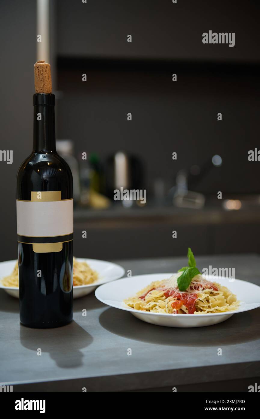 An elegant dinner setup featuring a bottle of wine and plates of pasta ...