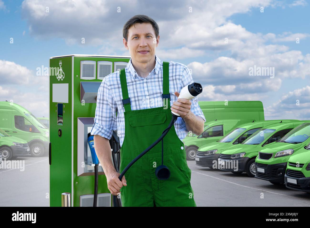 Man in uniform holds electric vehicle charging plug. Electric vans in ...