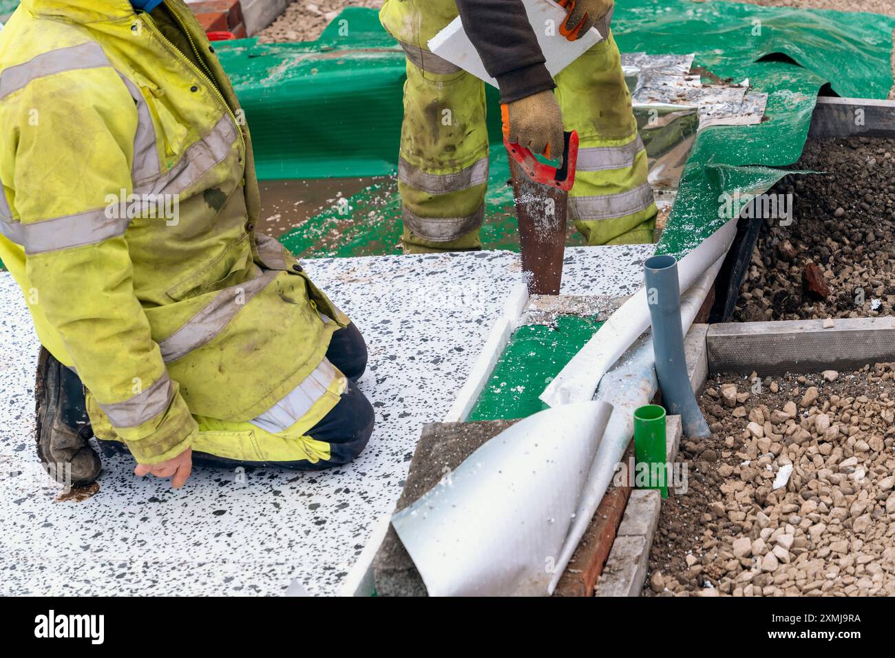 Builder placing polystyrene insulation boards on waterproofing membrane ...